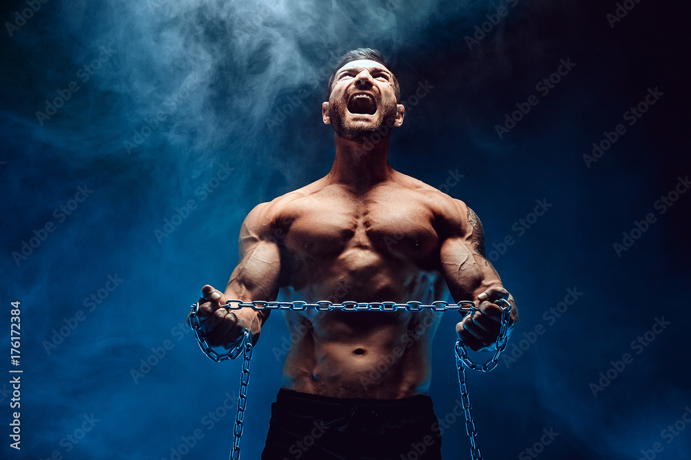 Shirtless bodybuilder man standing with chain and screaming. Try to ...