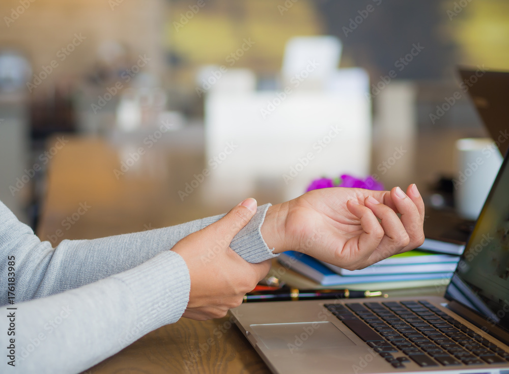 Closeup woman holding her wrist pain from using computer long time ...