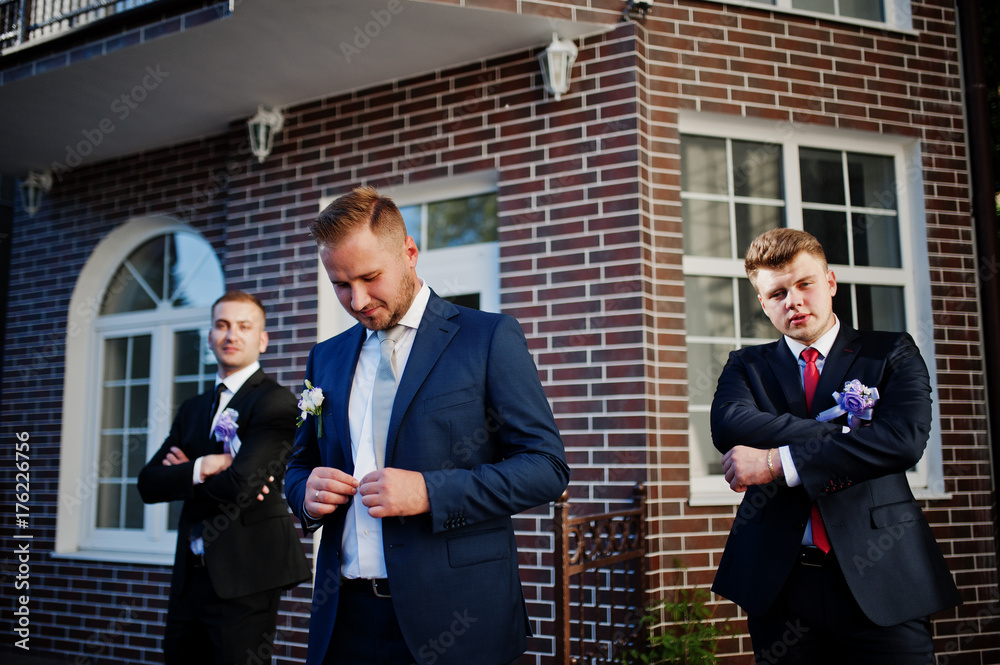 Handsome groom in his wedding tuxedo posing with groomsmen or best men ...