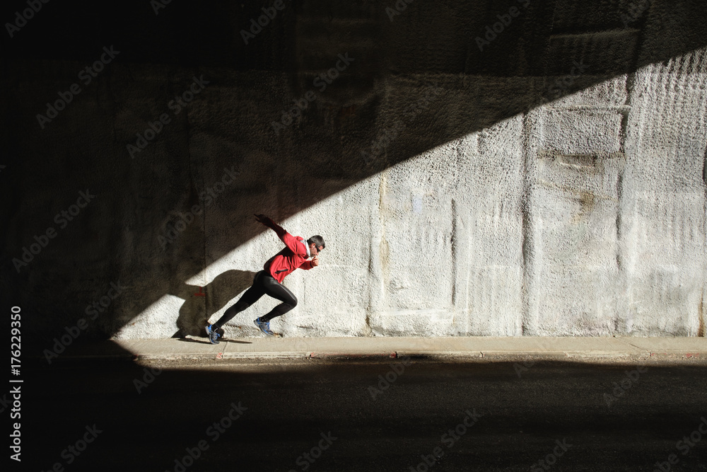 Powerful athlete sprinting and running. Man training and casting shadow ...