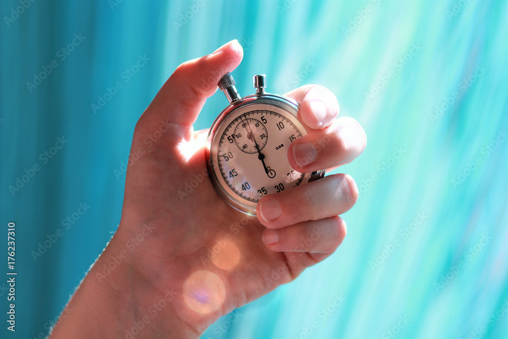 Hand holding a stopwatch and pressing the button to note the time. Sun ...