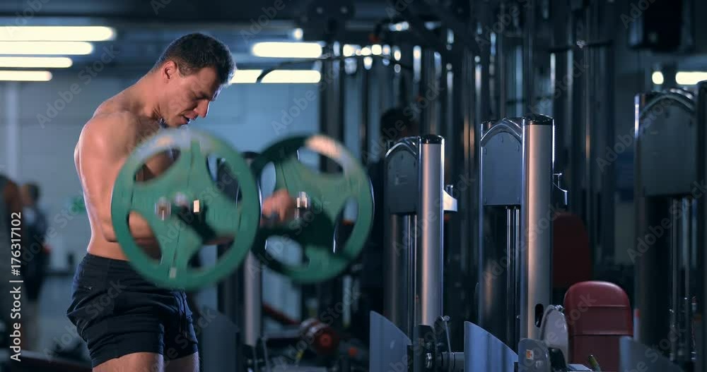 bodybuilder doing an exercise with a barbell in the gym. exercises for ...