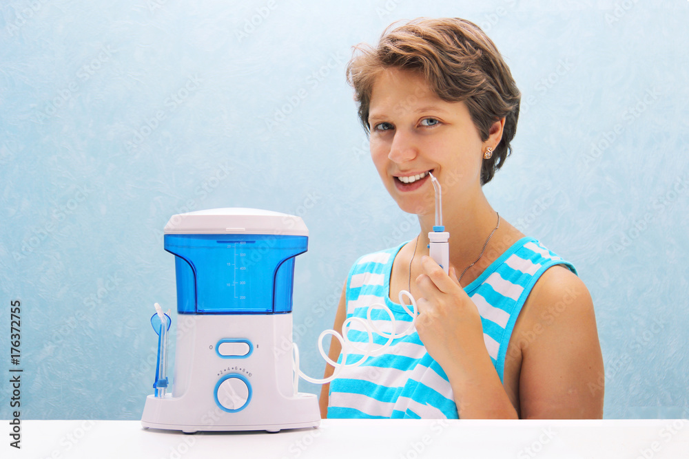 beautiful girl flushes her teeth with an oral irrigator. the woman ...