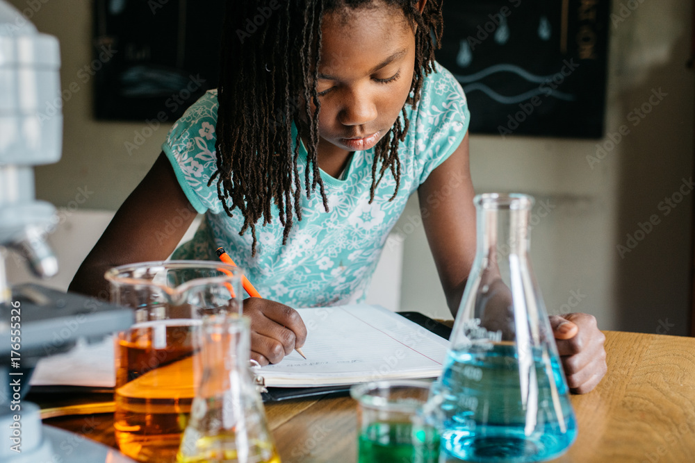 Girl writing notes in a science class Stock Photo | Adobe Stock