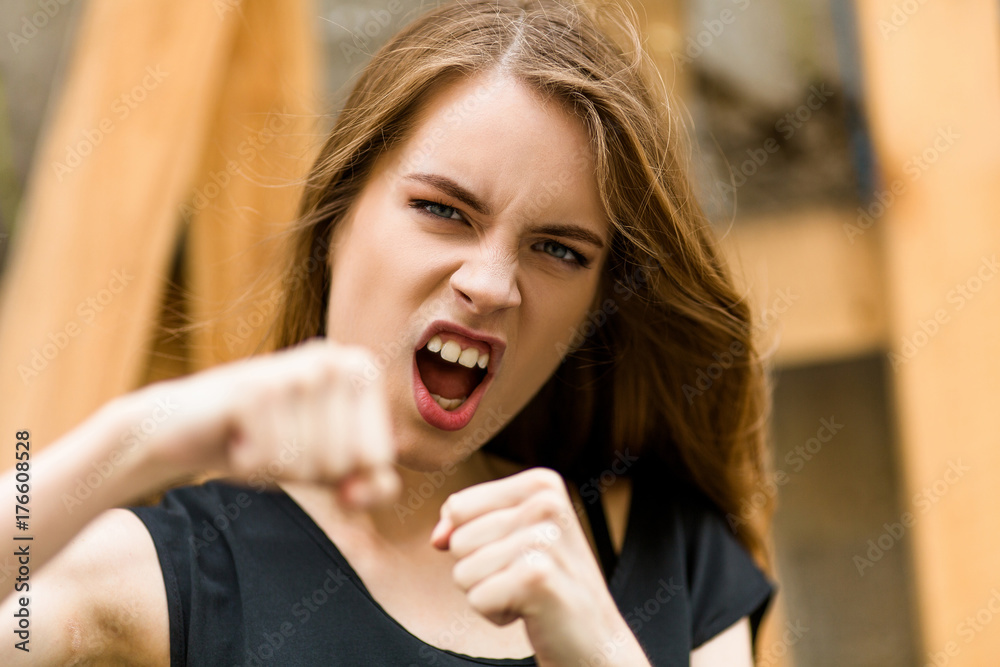 Beautiful young female showing fists. Pretty girl showing angry emotion ...
