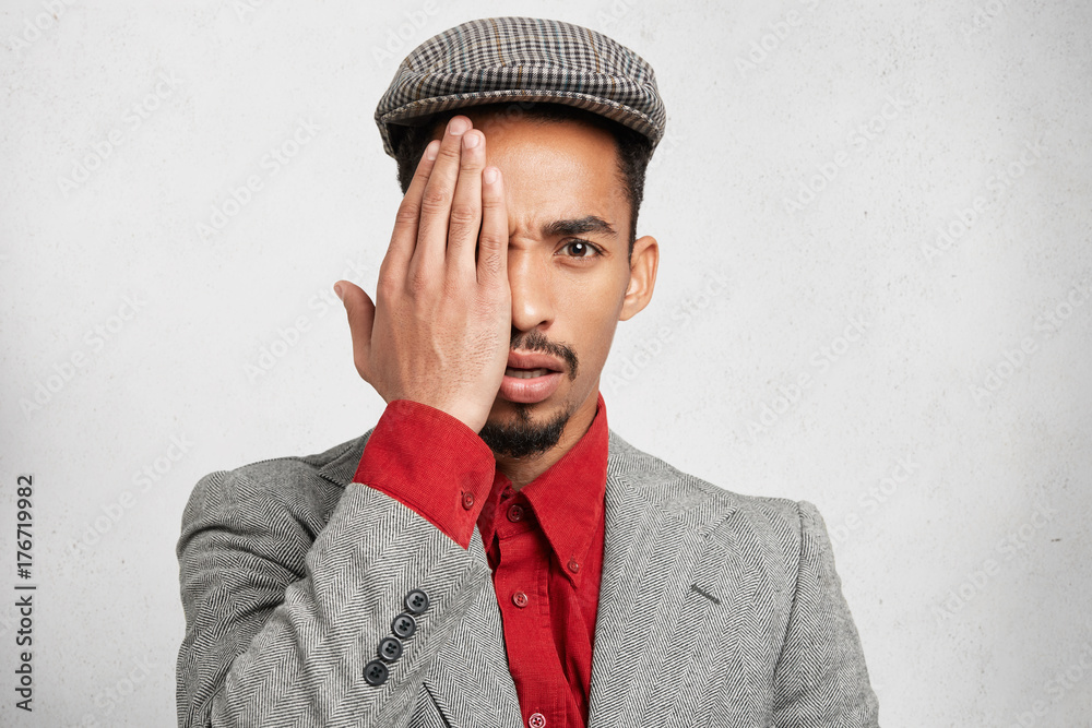 Portrait of attractive male wears cap, formal red shirt with jacket ...