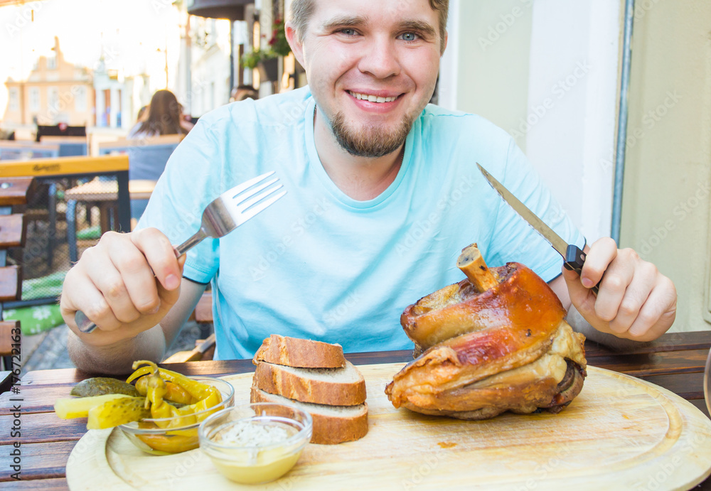 man eating knuckle of pork and drinks beer Stock Photo | Adobe Stock