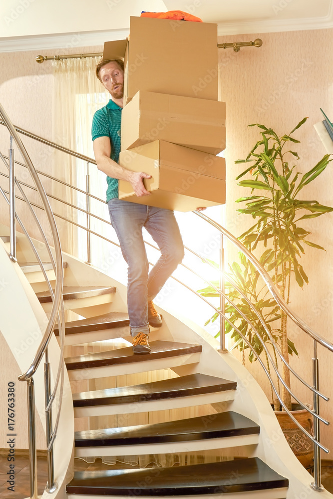 Man carrying stack of boxes. Young male walking downstairs. Common ...
