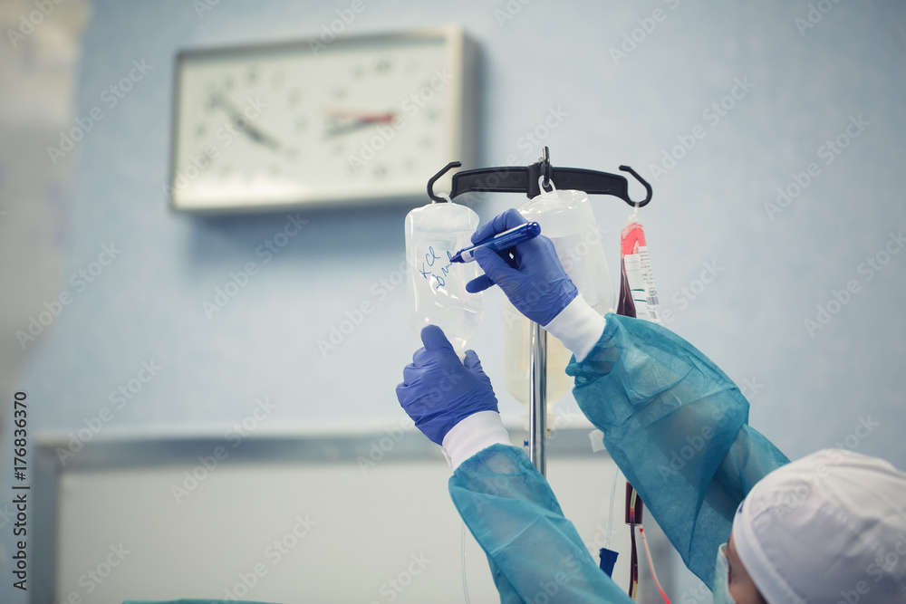 surgeon hand with sterile white gloves writes on an perfusion of ...