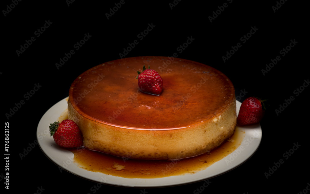 Flan recien hecho adornado con fresas y caramelo en fondo negro foto de ...