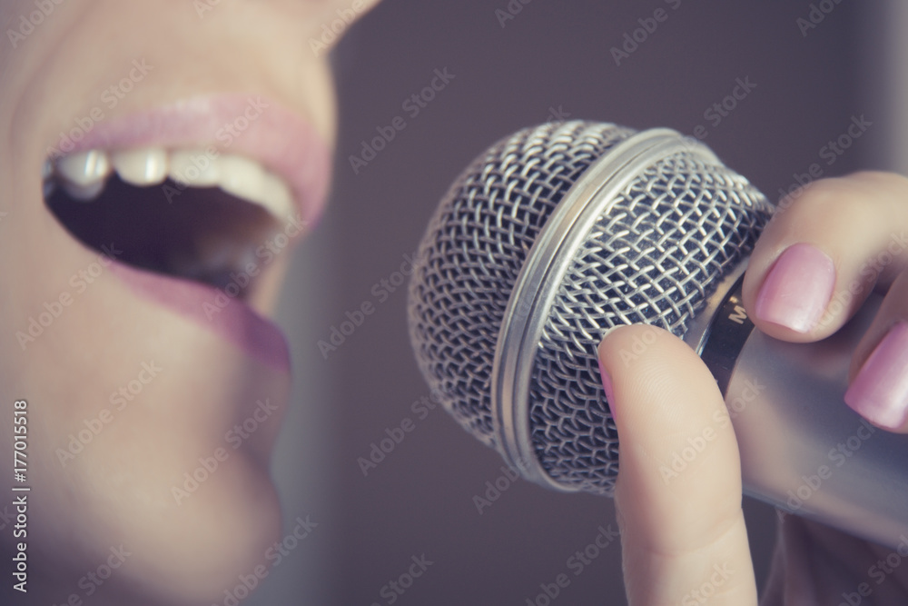 A woman sings into a microphone at a recording studio, her mouth close ...
