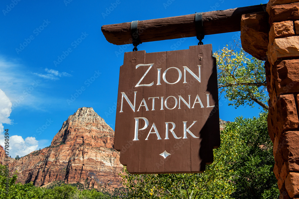 Zion National Park entrance sign: hanging wood panel with blue sky ...