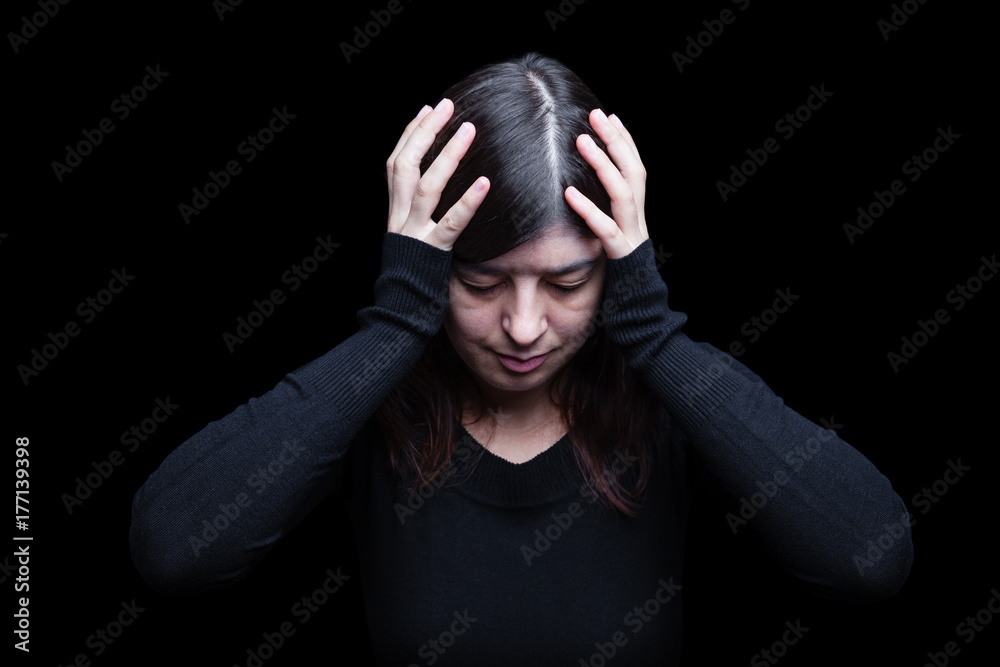 Distressed, woman holding the head with the hands, on a black or dark ...