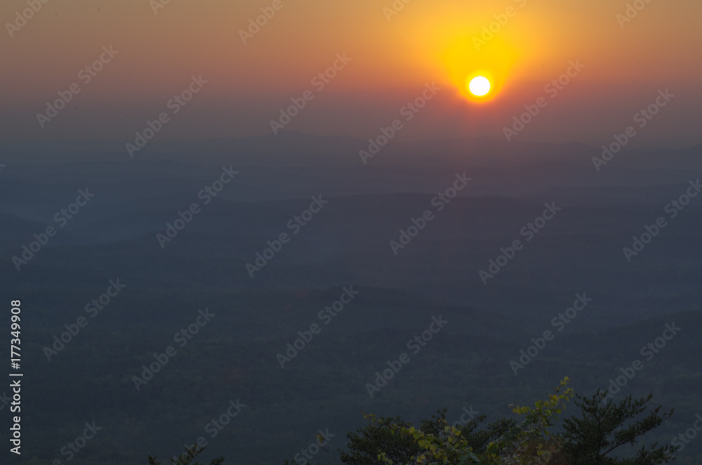 The sun prepares to dip below the horizon beyond the valleys visible ...