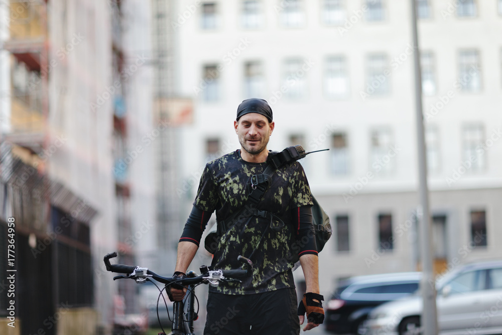 Bike Messenger Walking with his Bike Stock Photo | Adobe Stock