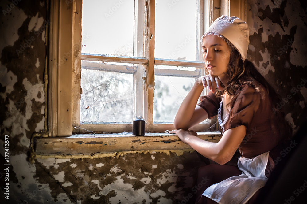 sad woman in a rustic dress sitting near window in old house feel ...