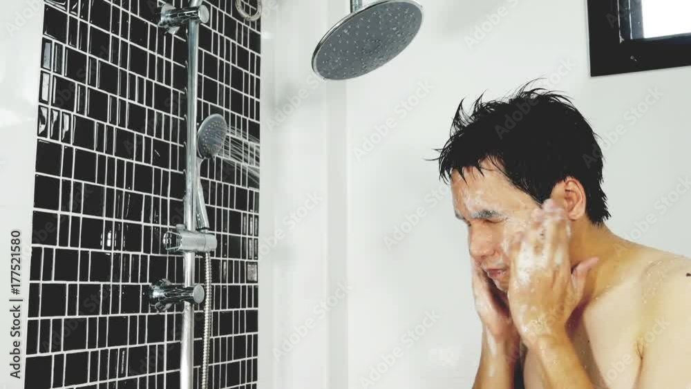 4k of Young man washing his face under shower in the bathroom. Handsome ...