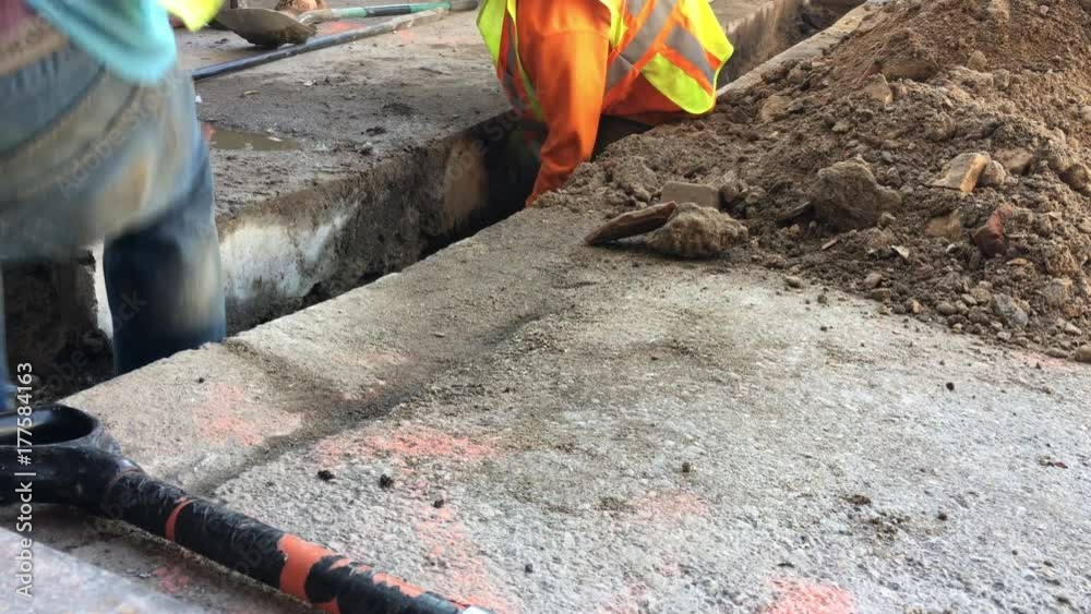 Men at work digging trench between slabs of concrete in downtown ...