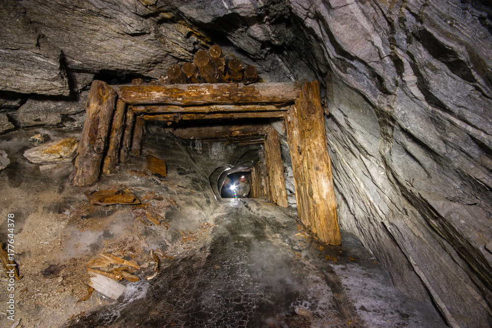 Old abandoned underground mica ore mine shaft tunnel with wooden stands ...