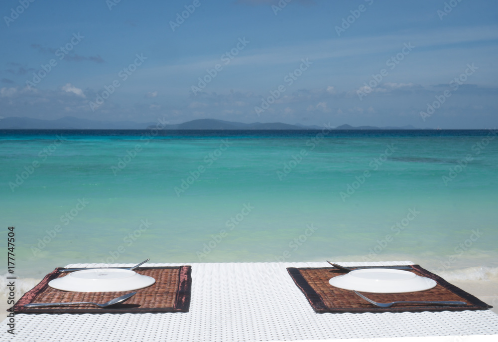 Table setting at the beach restaurant with beautiful blue sea and sky ...