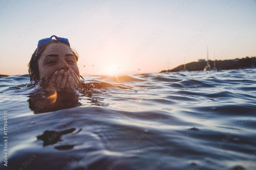 Young girl holding hands on her face while floating in water ภาพถ่าย ...