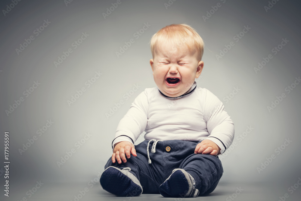 Crying baby sitting on the ground. Stock Photo | Adobe Stock