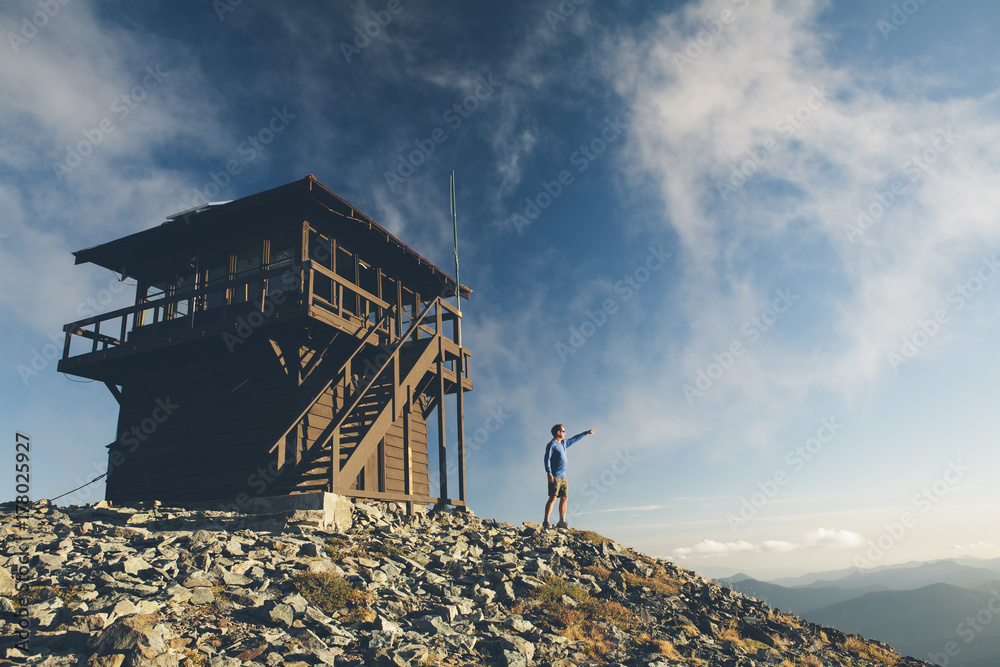 Man standing next to fire lookout on mountain summit, dusk Stock Photo ...