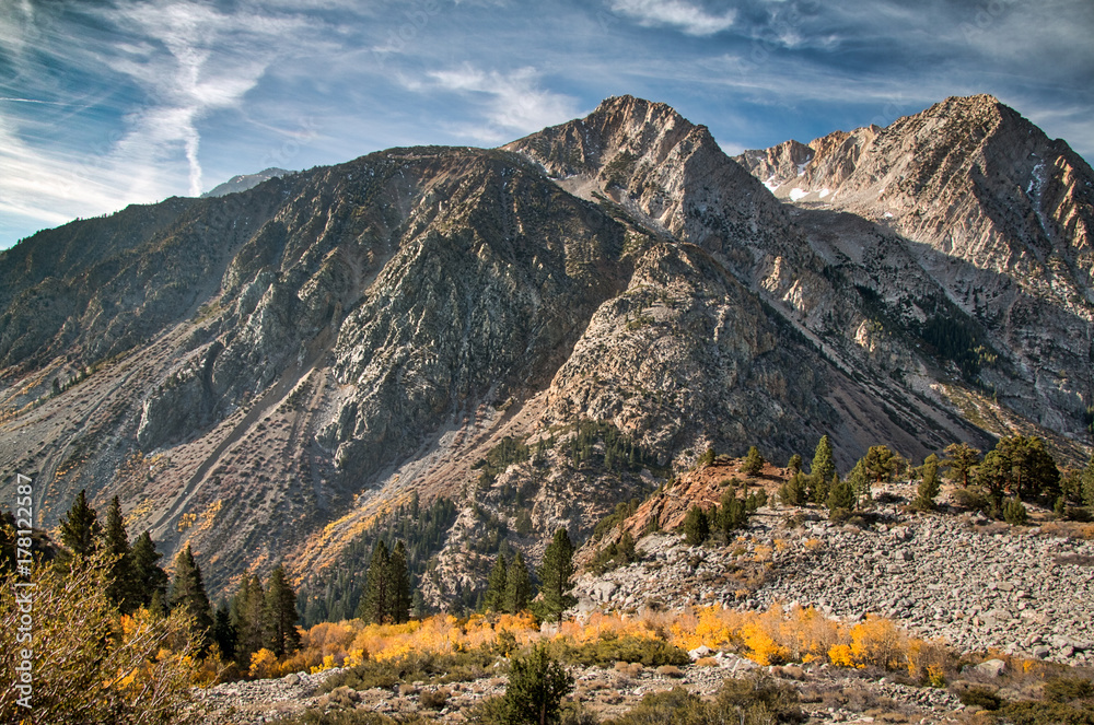 Dramatic granite faced mountains rise rapidly from a canyon with aspen ...