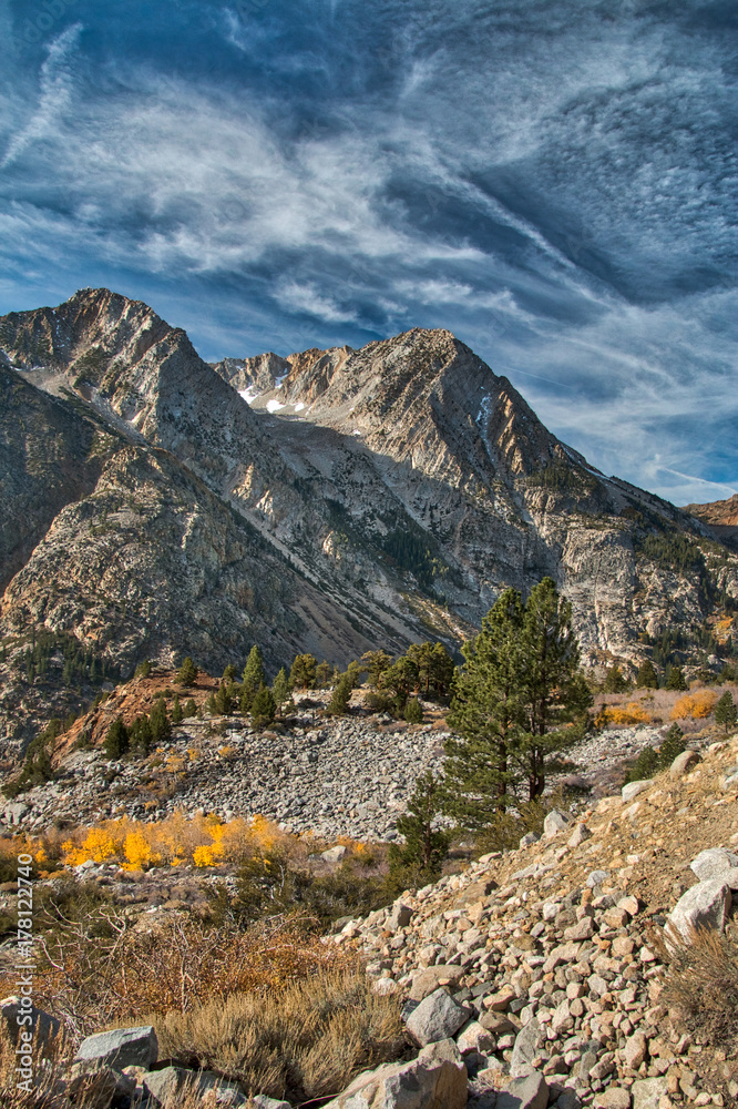 Dramatic granite faced mountains rise rapidly from a canyon with aspen ...