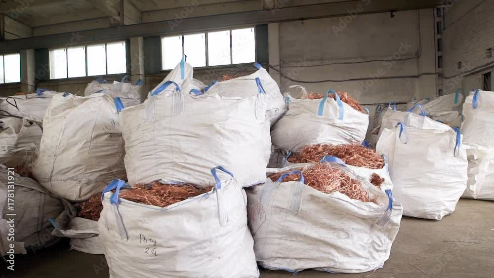 huge white bags with copper scrap from wires are lying in a warehouse ...