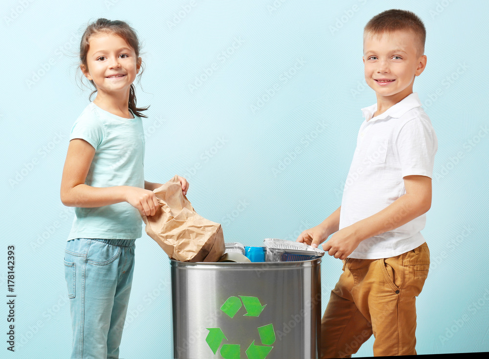 Little children throwing garbage into litter bin on color background ...