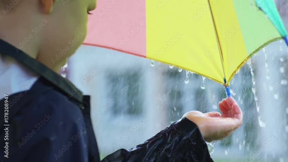 Cinemagraph of little boy holding umbrella and catching raindrops in ...