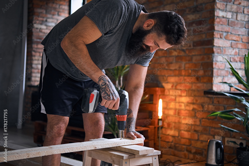 Carpenter drilling a hole in a board in a room with loft interio Stock ...