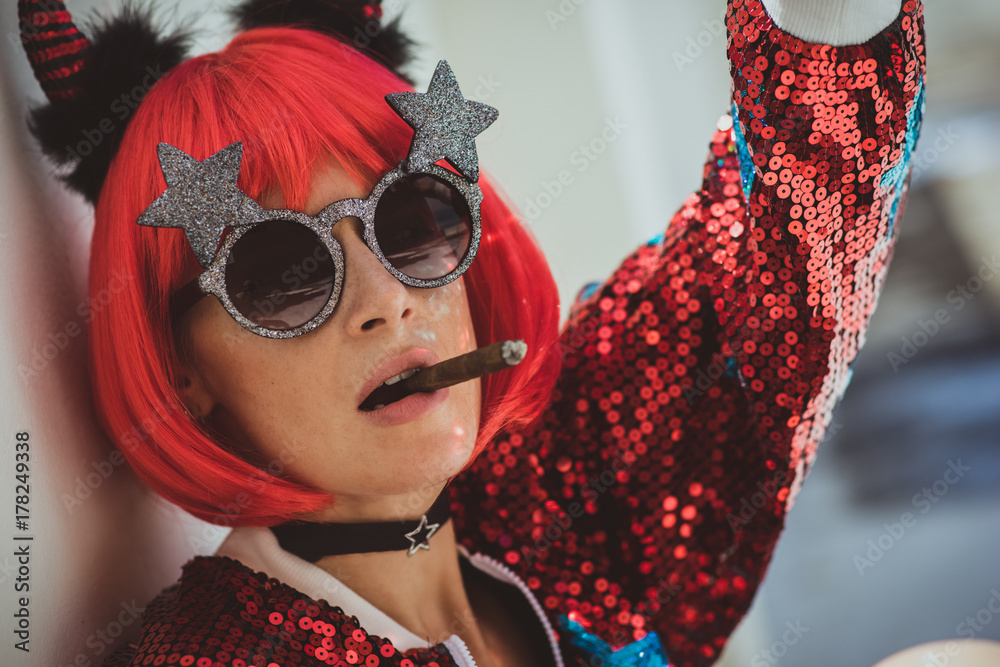 Beautiful girl devil sitting on white background and smoke cigar. In ...