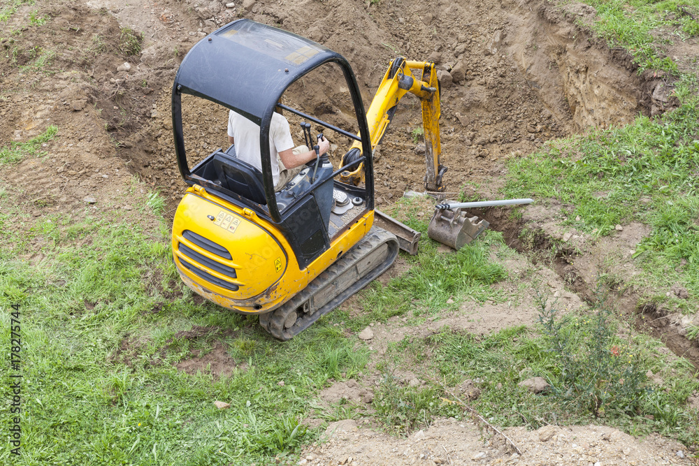 Foto Stock Workman using a mini digger to dig a hole for a swimming ...