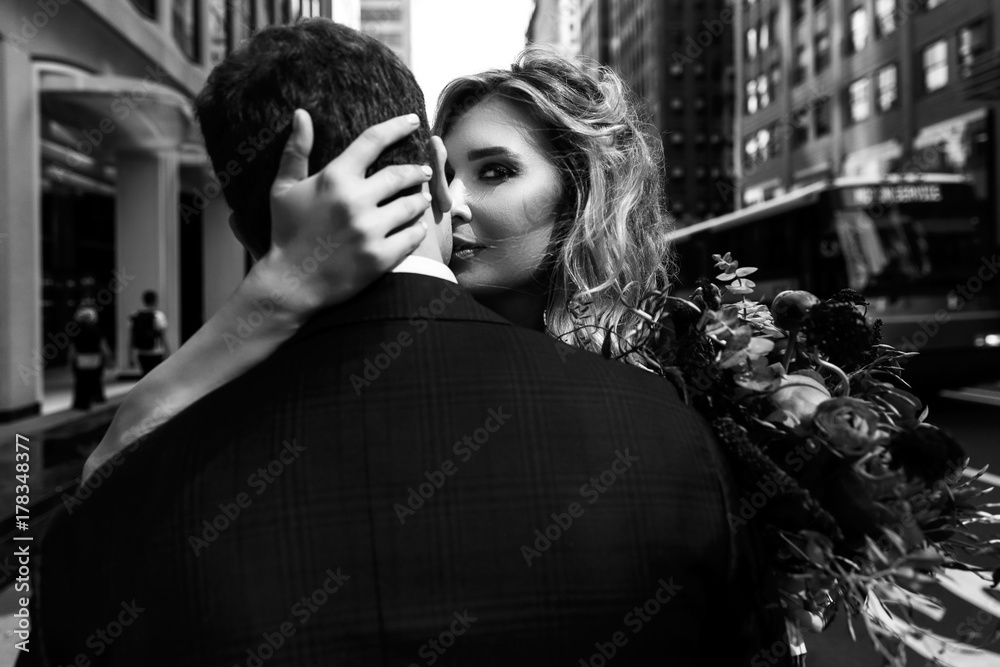 Bride looks over groom's shoulder hugging with him somewhere in New ...