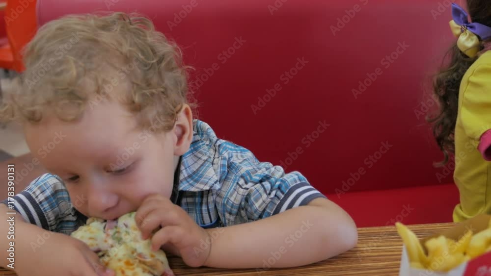 Little kid boy close-up eating french fries in a fast food restaurant ...
