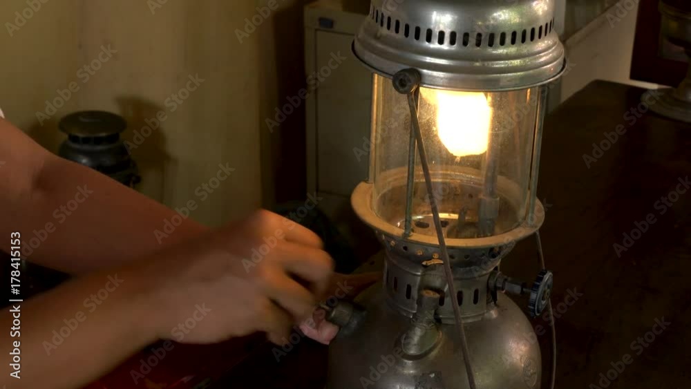 Asian man using pump handle to light a pressurized kerosene lantern ...
