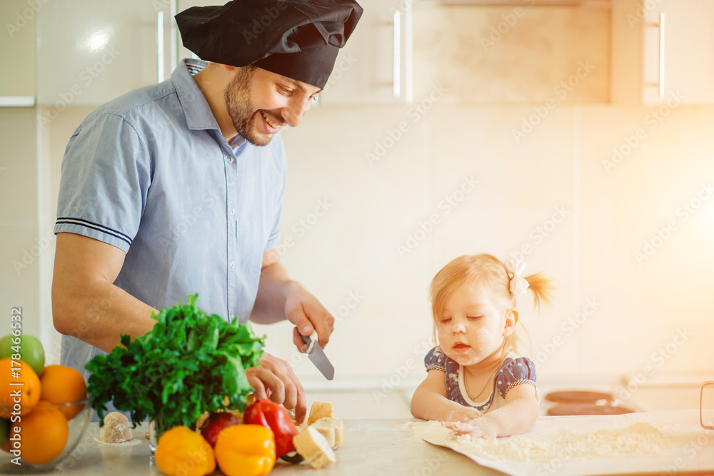 Cute little girl and her handsome dad smiling while cooking in kitchen ...