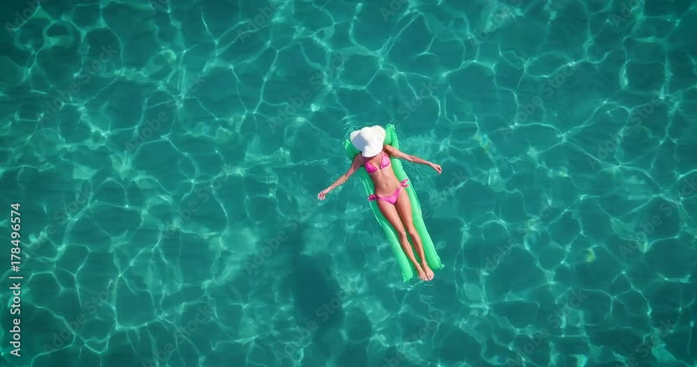 A beautiful young girl is lying on a mattress in the open sea or in the ...