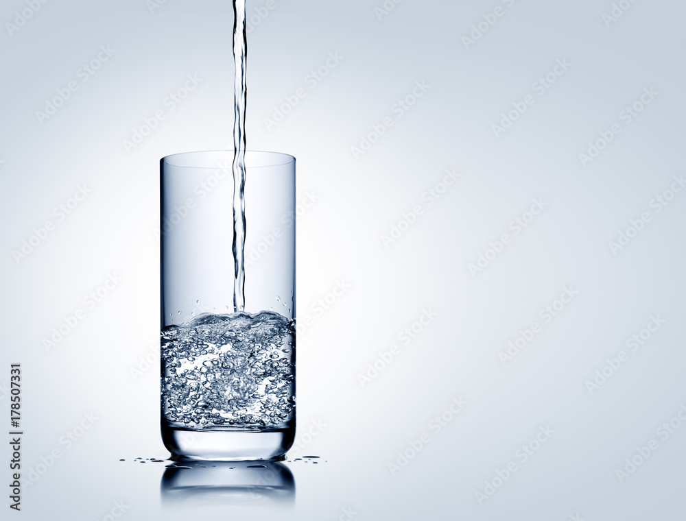 Water pouring and splashing into half full, half empty glass with ...