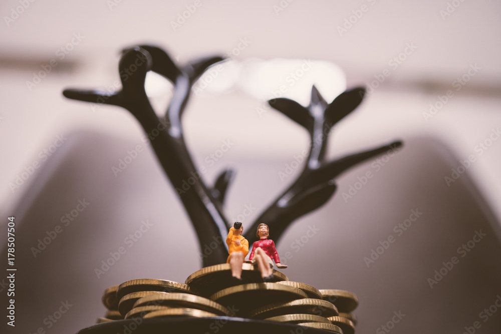 Miniature people, couple woman sitting on stack coins used for ...
