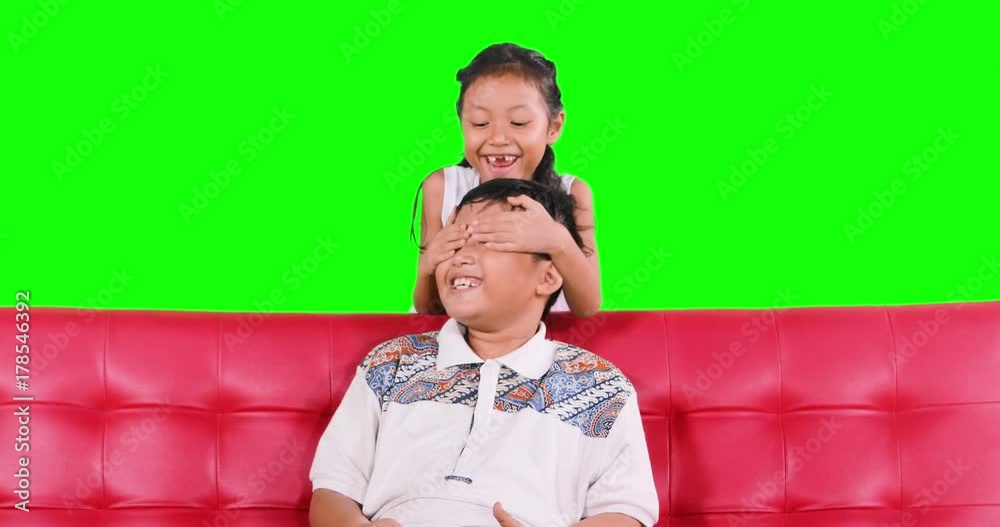 Toothless little girl closing her brother eyes while sitting on the ...