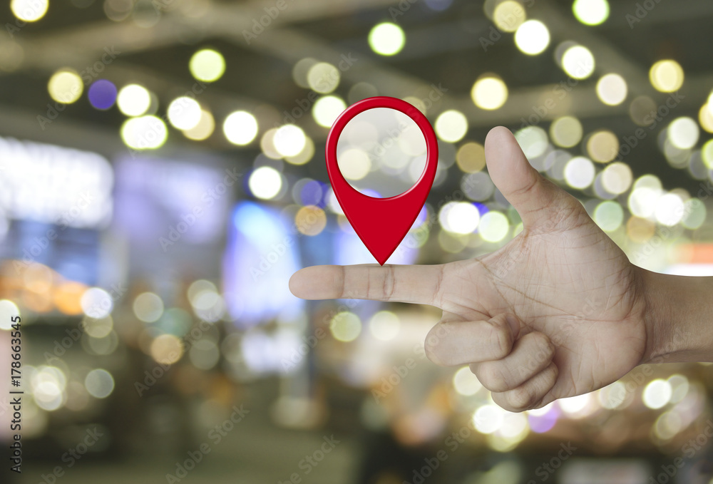 Map pin location button on finger over blur light and shadow of ...