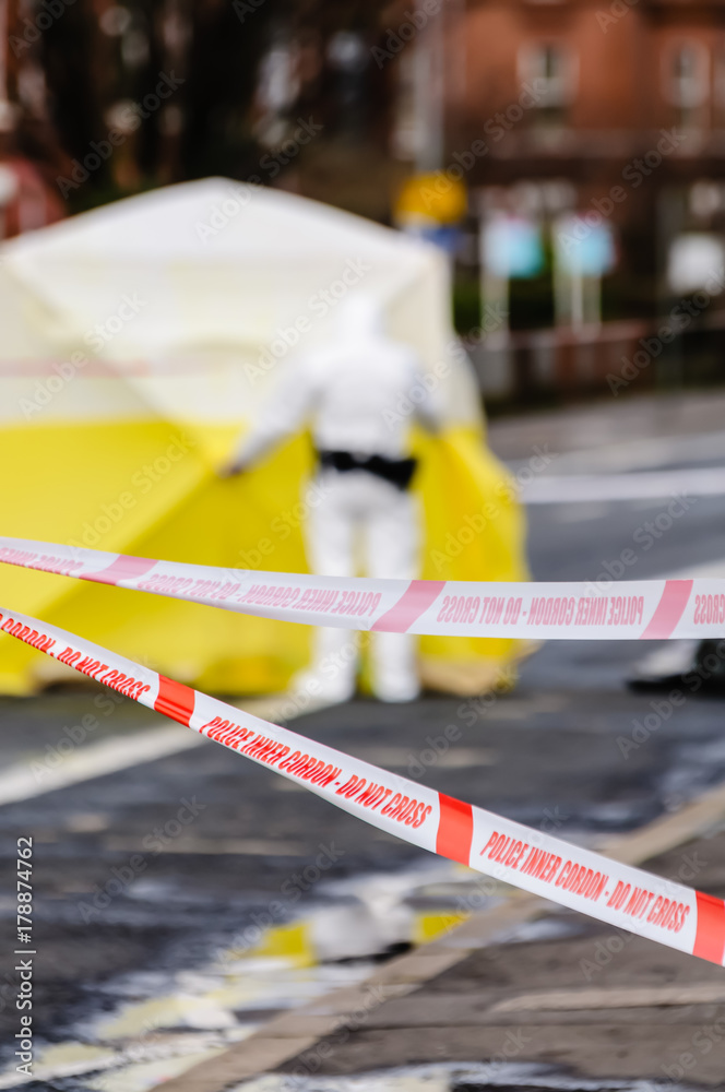 A scene of crime officer wearing a white boiler suit looks inside an ...