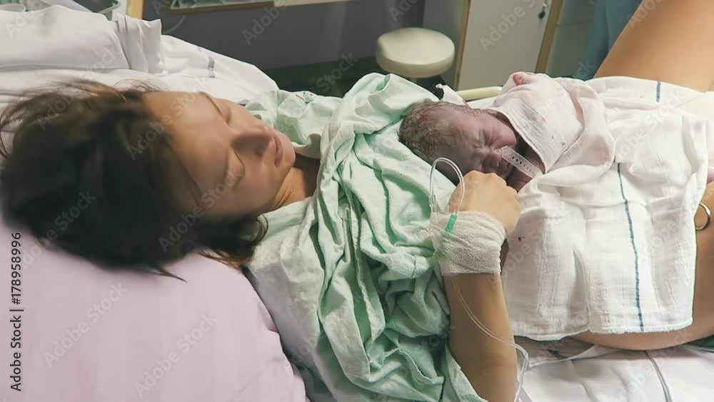Childbirth. Mother holding her newborn baby child after labor in a ...