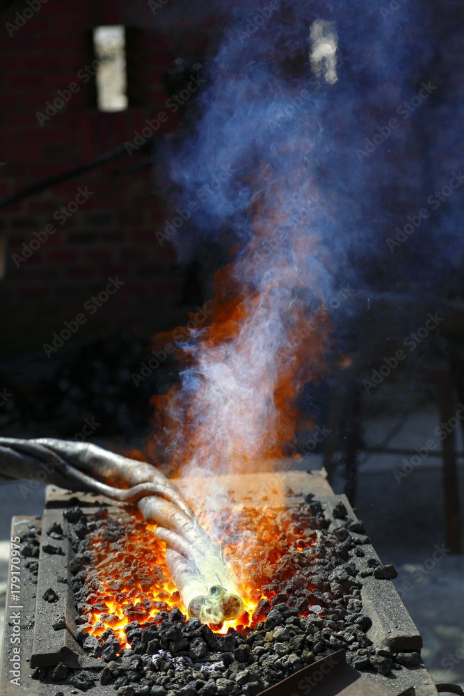Blue smoke on a black background. The work of the blacksmith. The hot ...