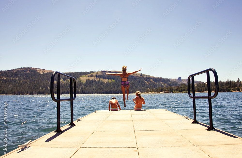 Woman jumping off the dock with her arms out - into a lake between two ...