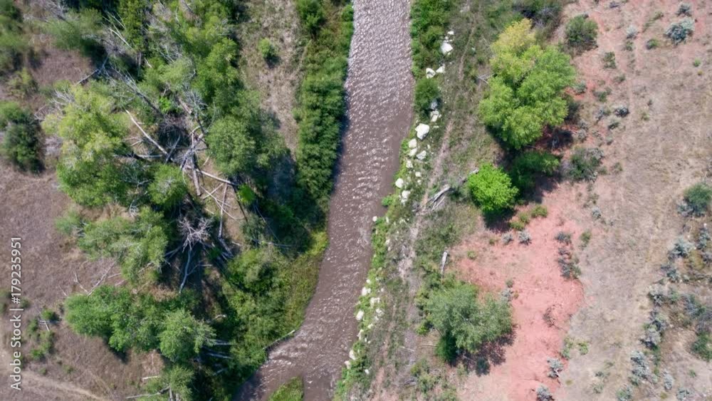 Top down aerial view of river flowing downstream through the green ...