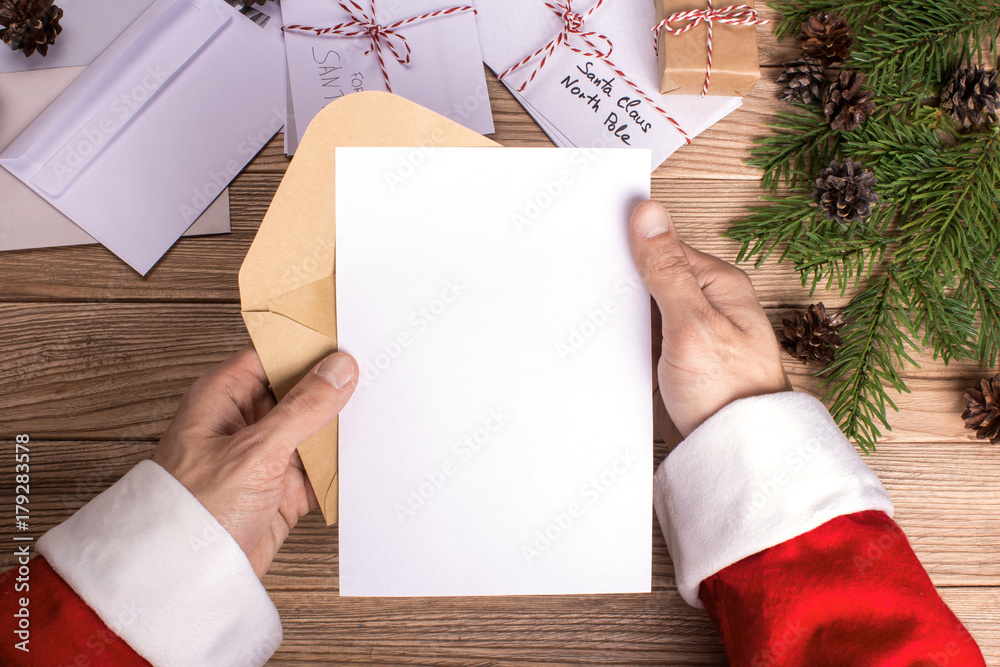 Santa Claus reads letters and holds them in his hands. Mock-up letter ...